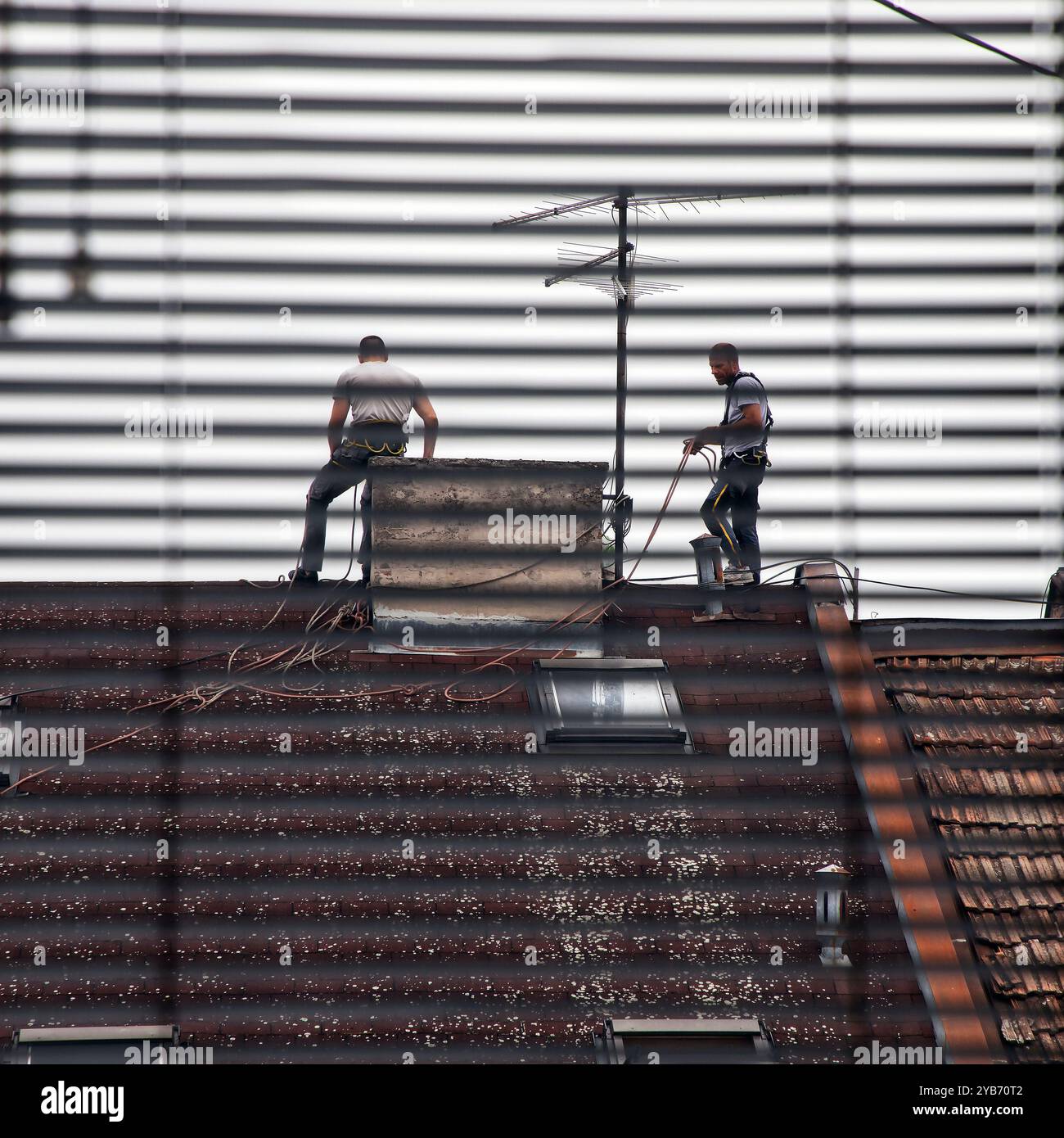 Rooftop workers seen through a window Stock Photo - Alamy