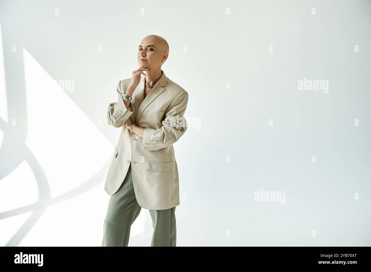 A confident young bald woman poses thoughtfully in chic clothing ...