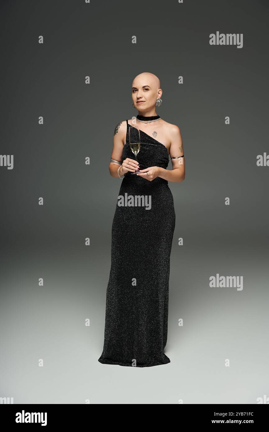 A young bald woman with alopecia stands elegantly, holding a glass ...