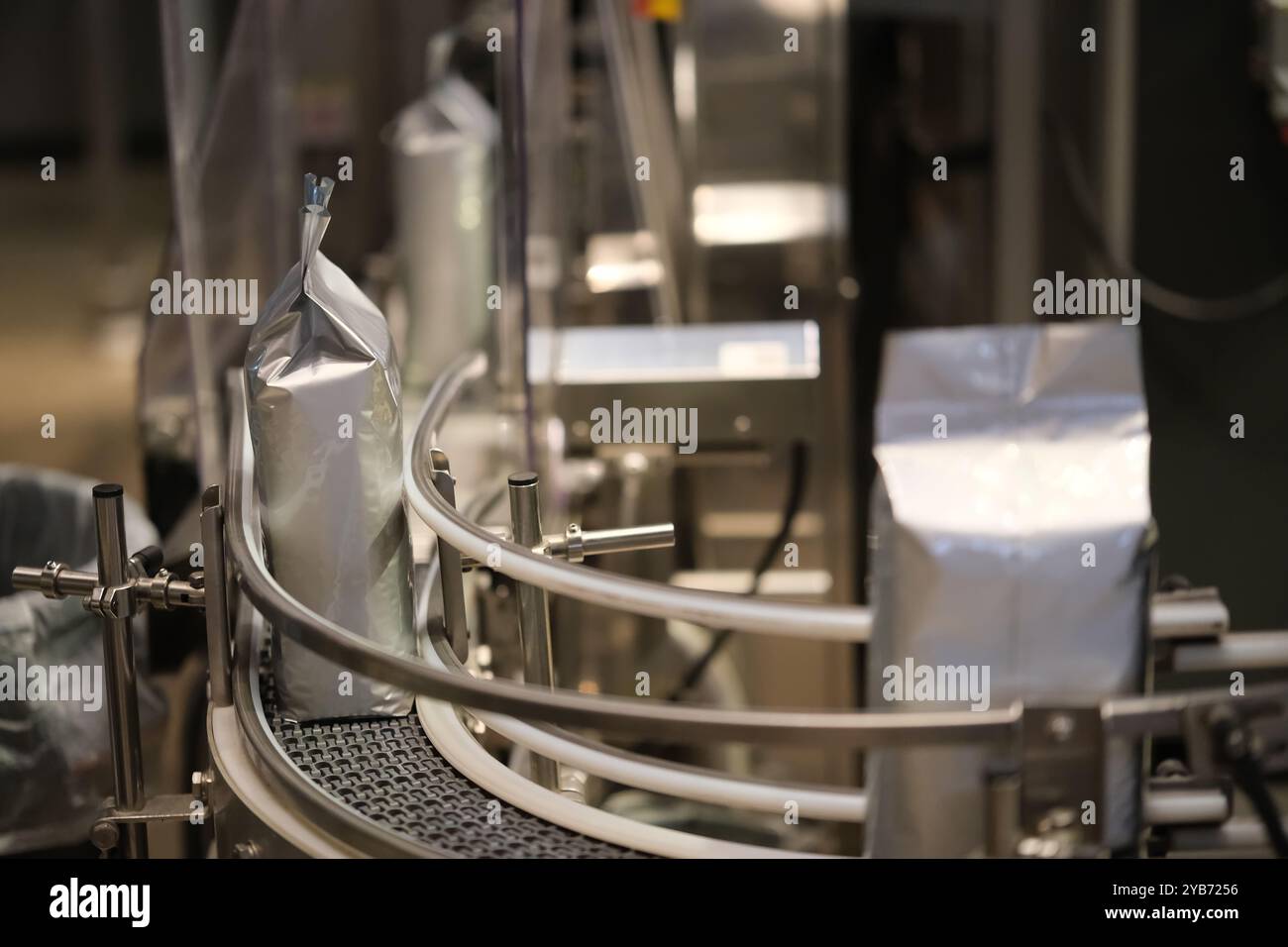 roasted coffee beans in package on conveyor belt in factory. Coffee ...