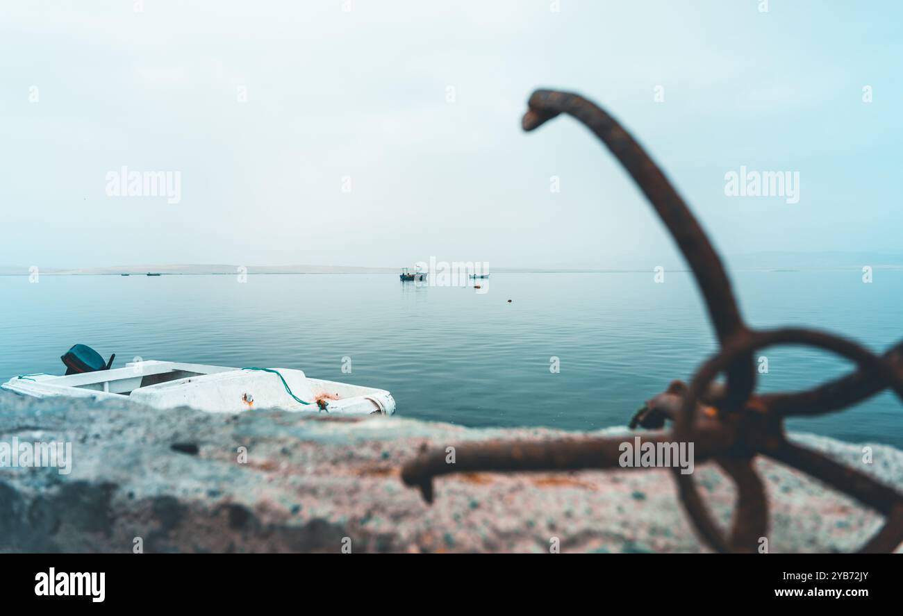 A rusty anchor is on the side of a wall next to a body of water Stock ...