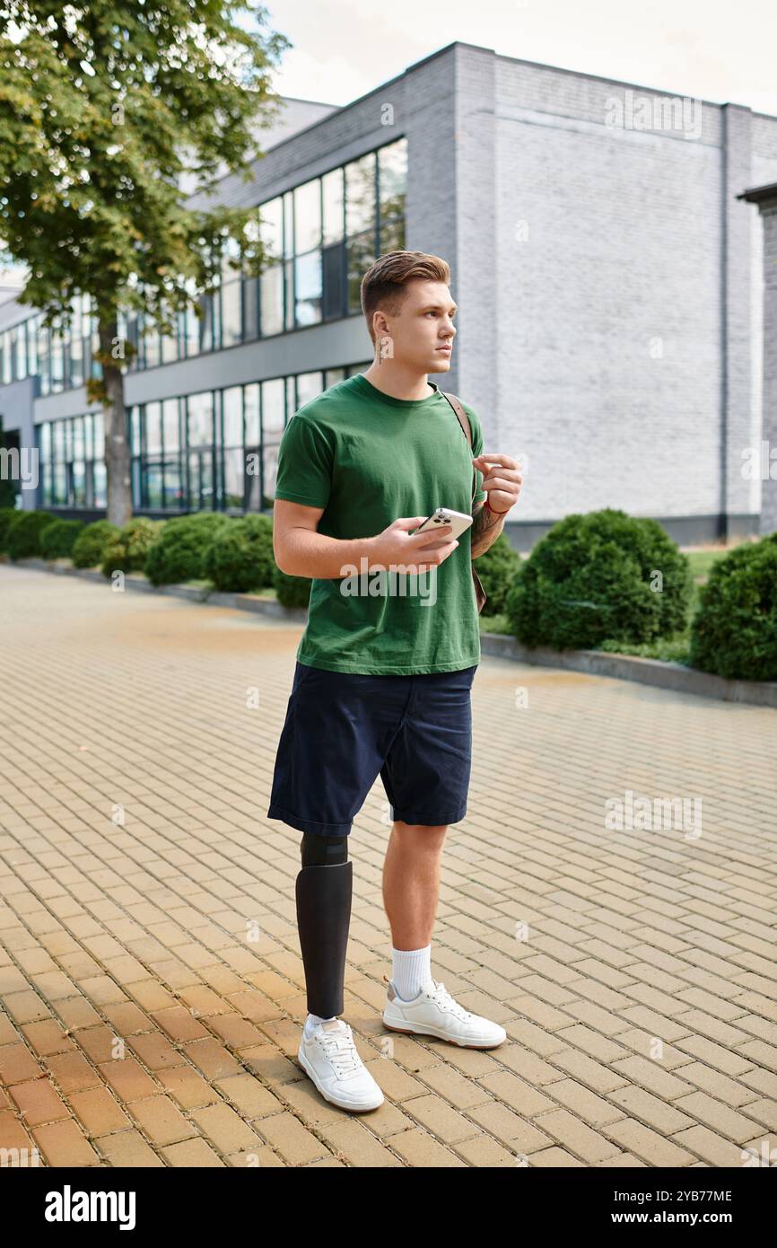 A handsome man with a prosthetic leg stands outside, holding his phone ...
