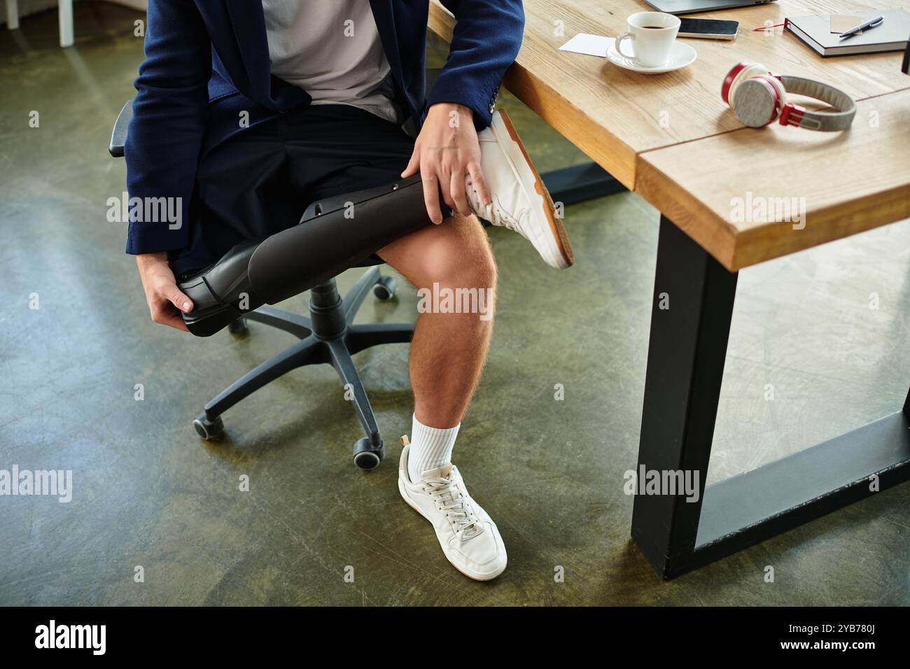 A young businessman with a disability adjusts his prosthetic limb while ...