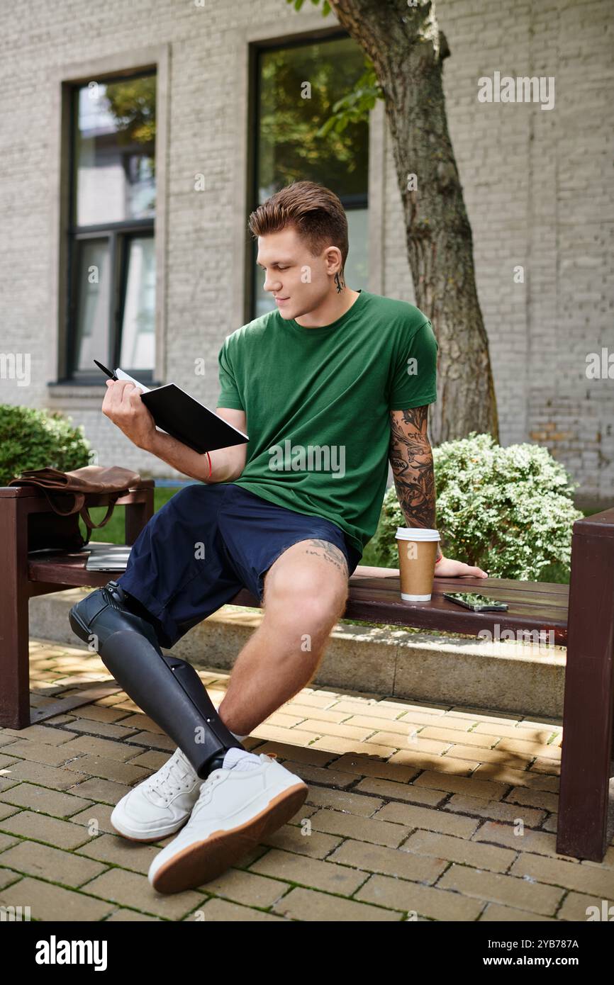 A young man with a prosthetic leg sits on a bench, writing in a ...