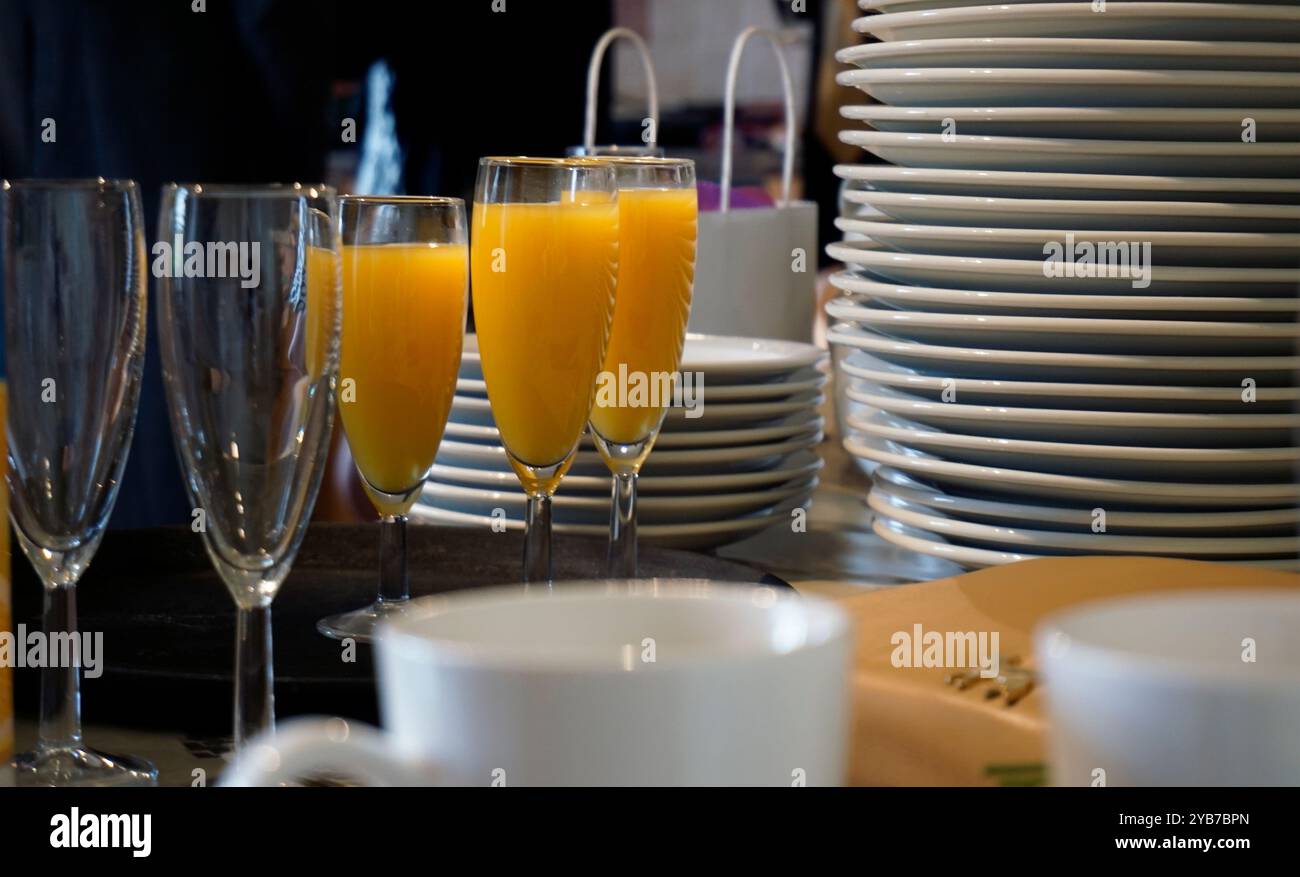 pile of plates and glasses of orange juice at wedding reception buffet ...