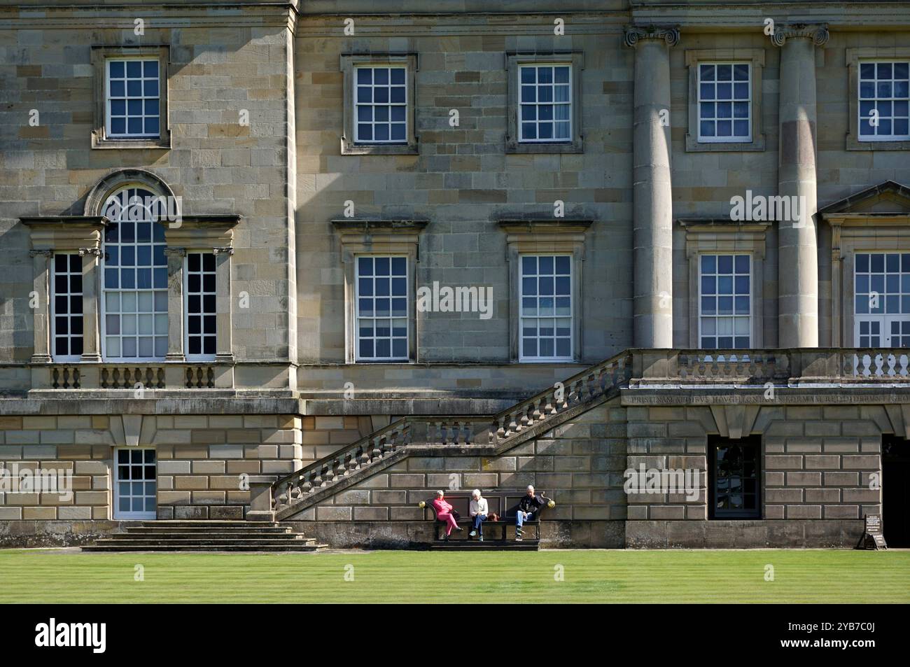 three people seated being dwarfed by architectural frontage of houghton ...