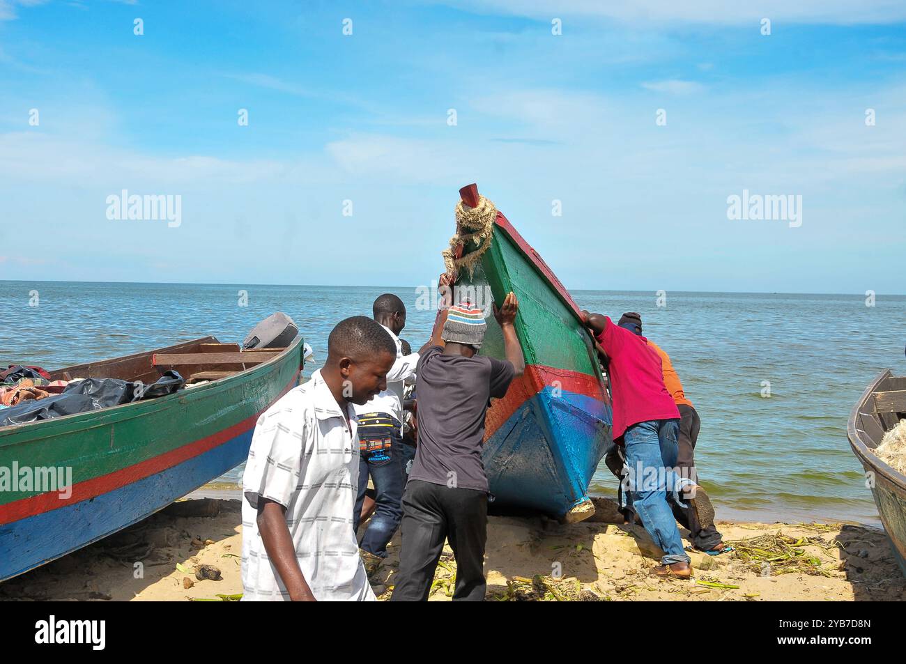 Fishermen pushing a boat into Lake Victoria at Kasensero fishing town ...