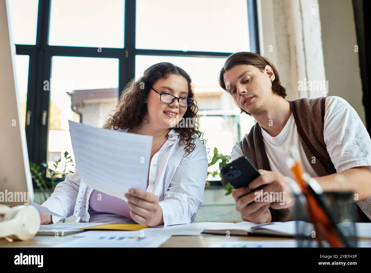 A young plus size woman and her male friend work together, sharing ...
