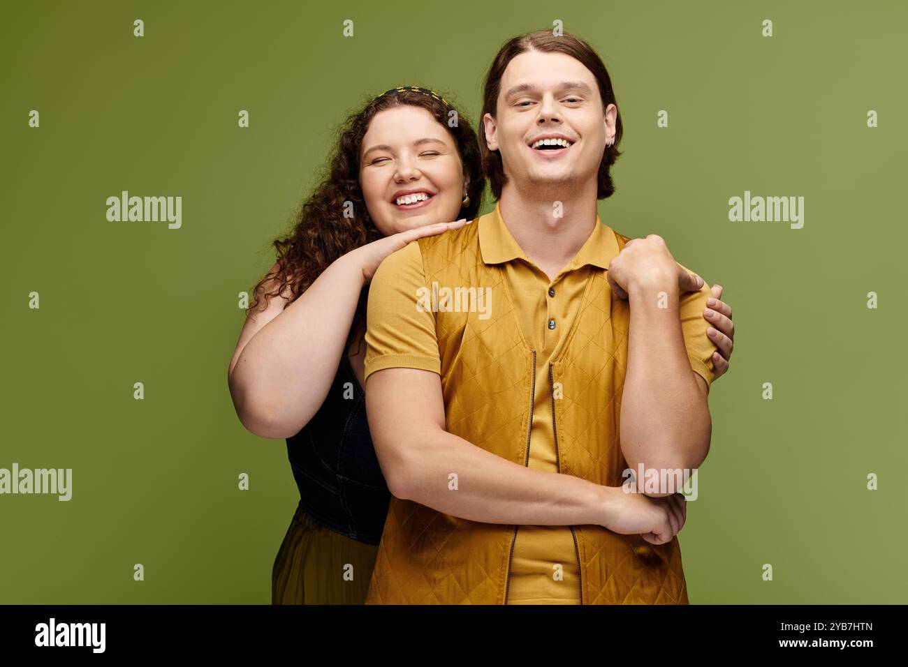 Two friends happily pose together in a studio with a bright green ...