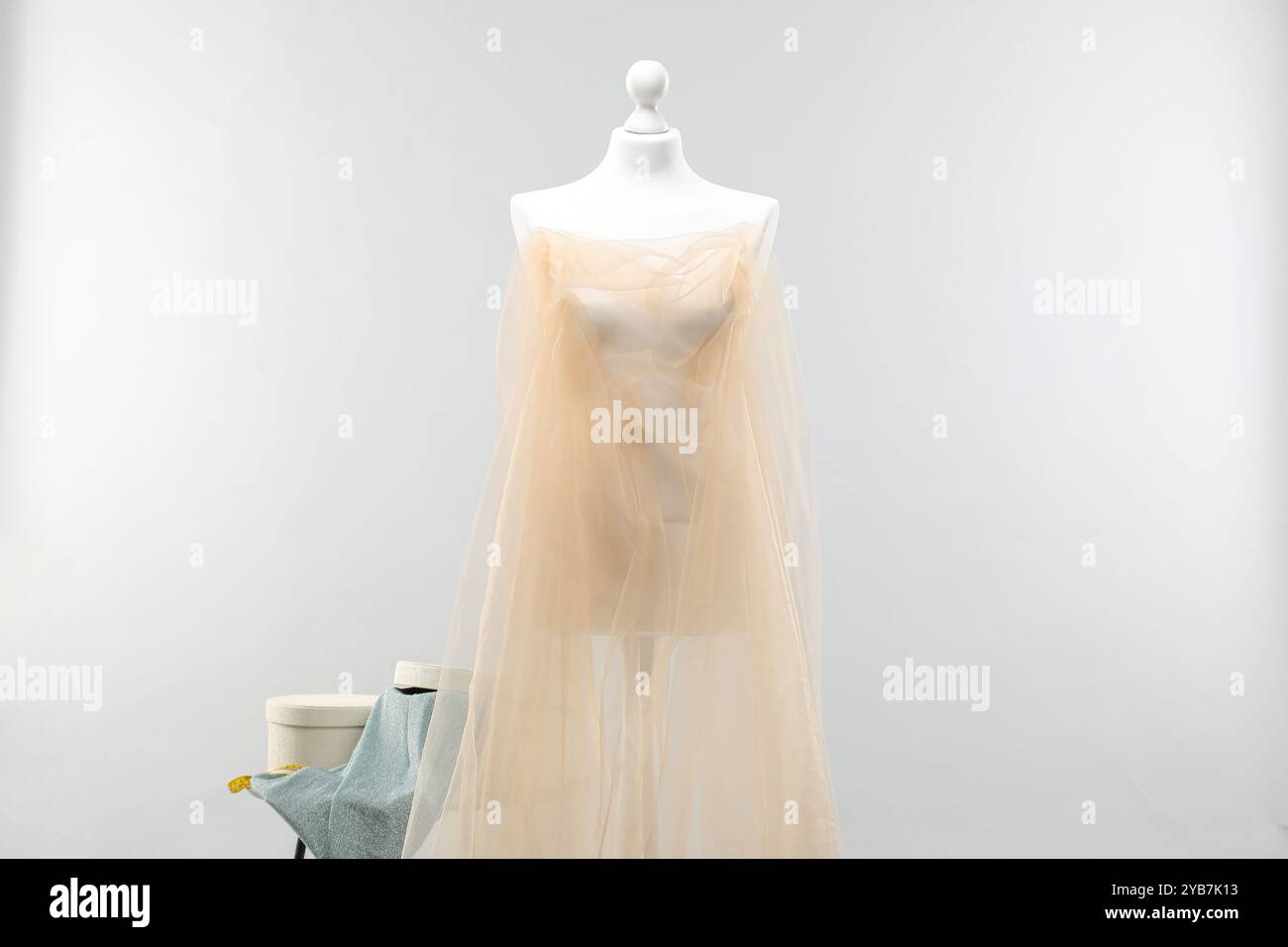 Mannequin with fabric and boxes on side table against light grey ...
