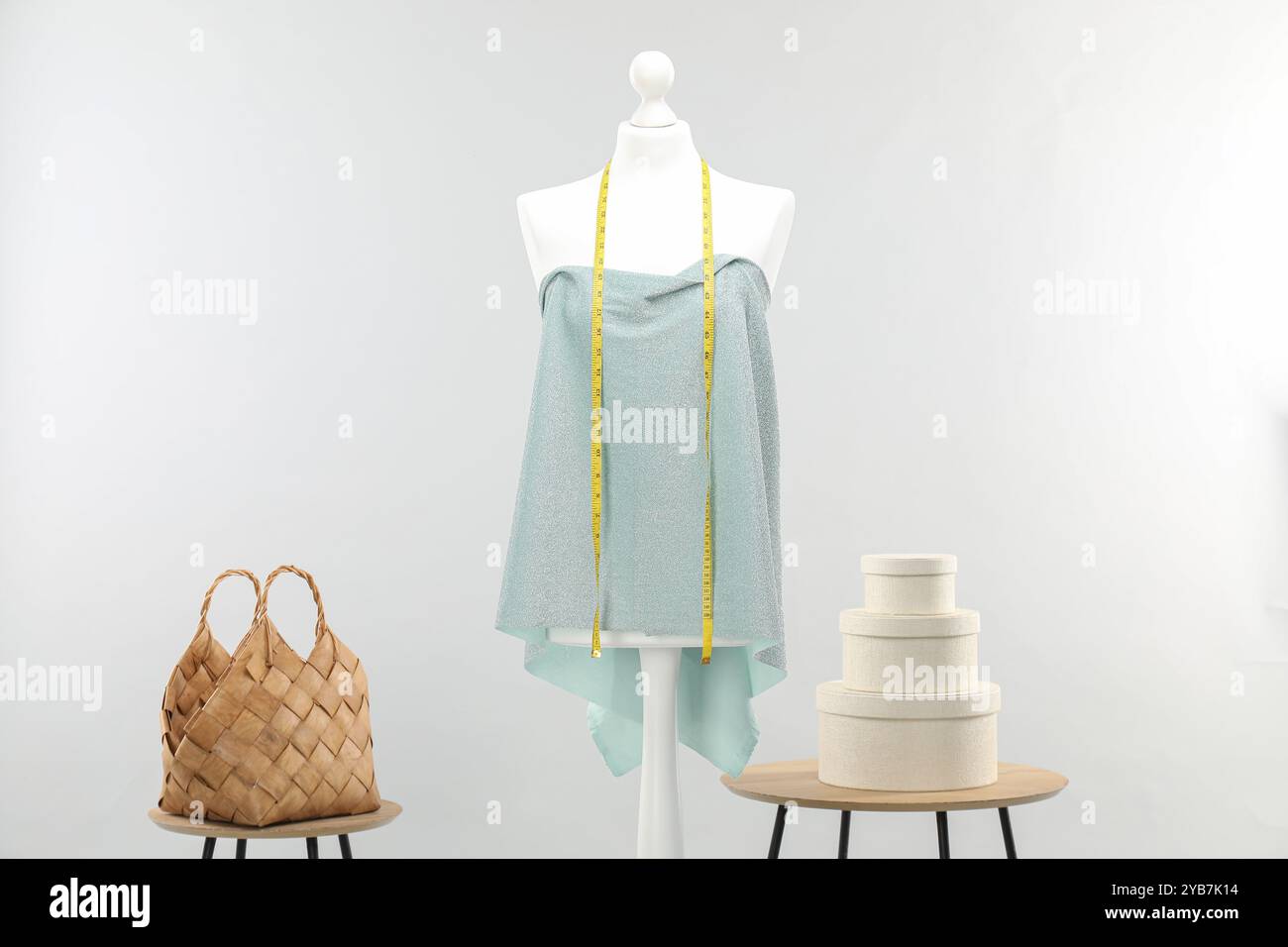 Mannequin with measuring tape, fabric, bag and boxes on side tables ...