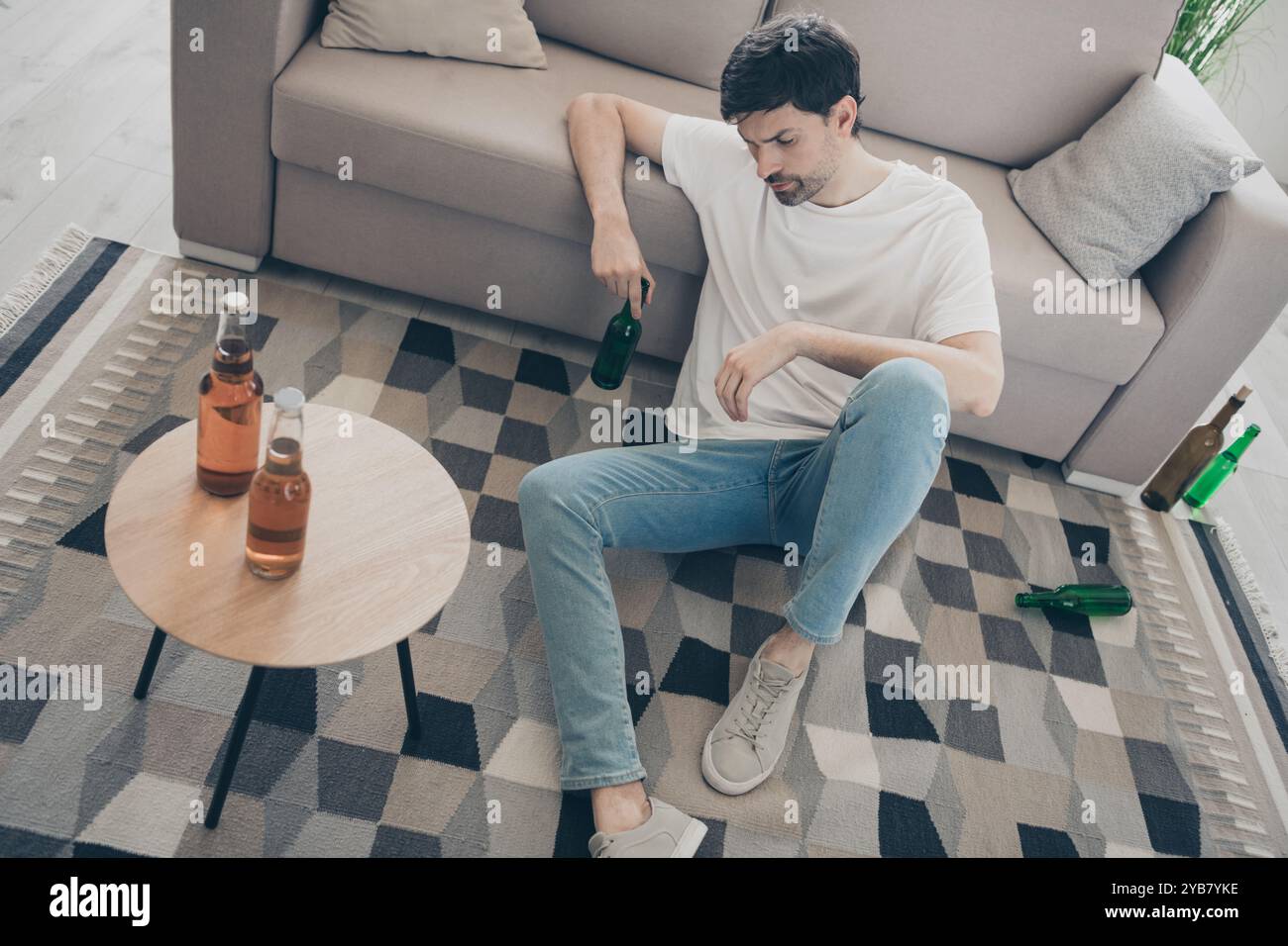 Man relaxing indoors on weekend, sitting on floor of modern home ...