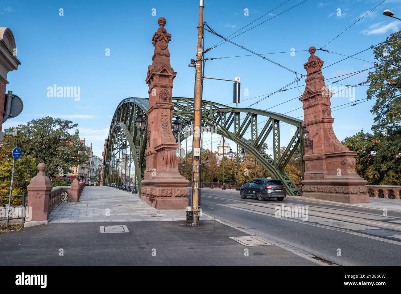A historic steel arch bridge with intricate stone pillars under a clear ...