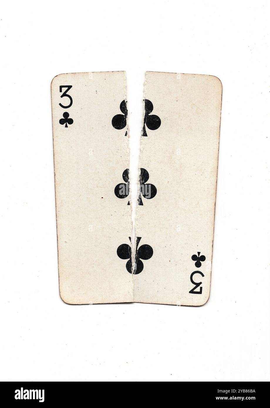 A vintage playing card torn in half from top to bottom on a white ...