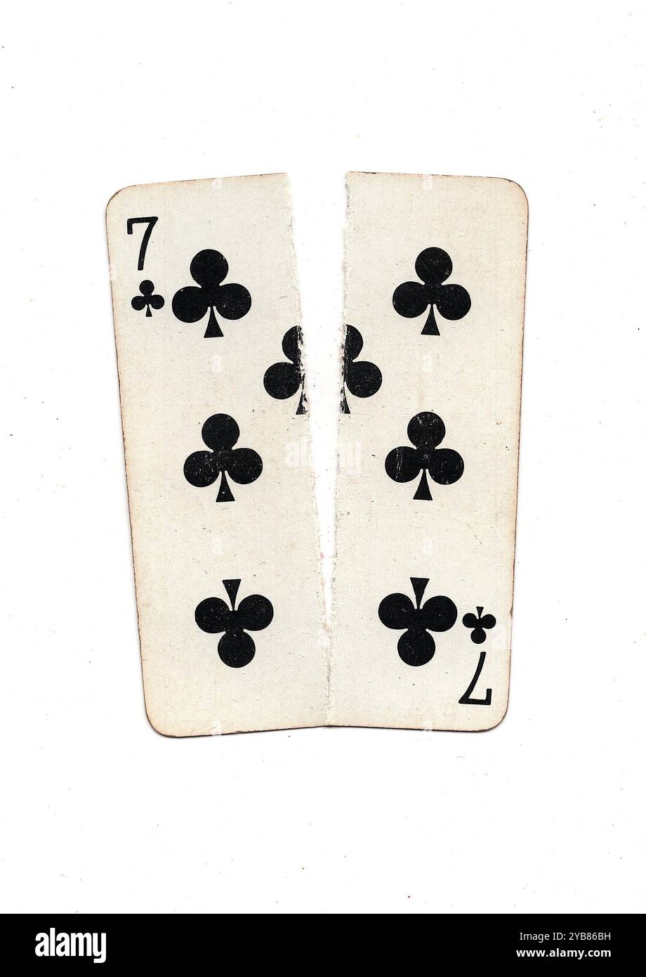A vintage playing card torn in half from top to bottom on a white ...