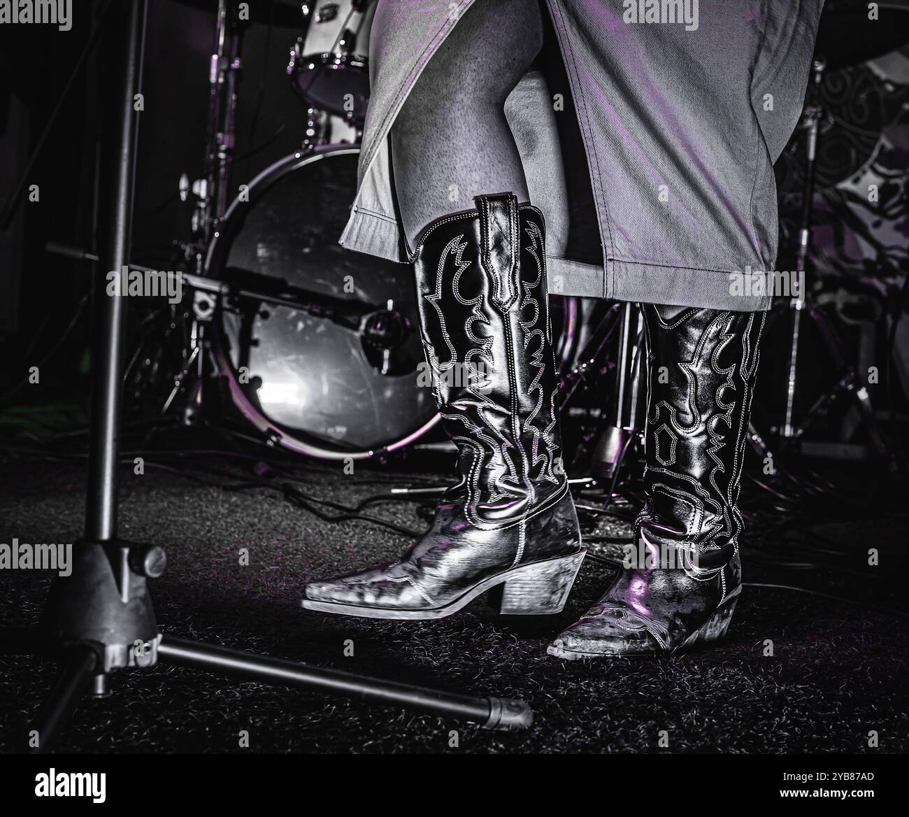 Cowboy boots close-up on female singer with mic stand and drums at a ...