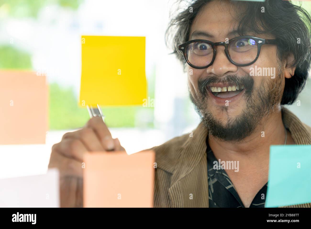 A young businessman is writing business ideas on a sticky note Stock ...