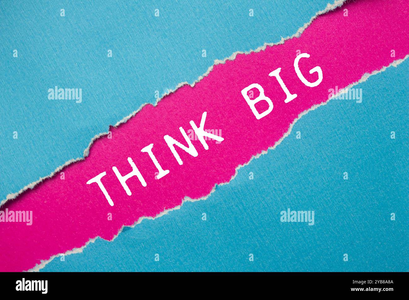 Think big message written on ripped torn blue paper with pink ...