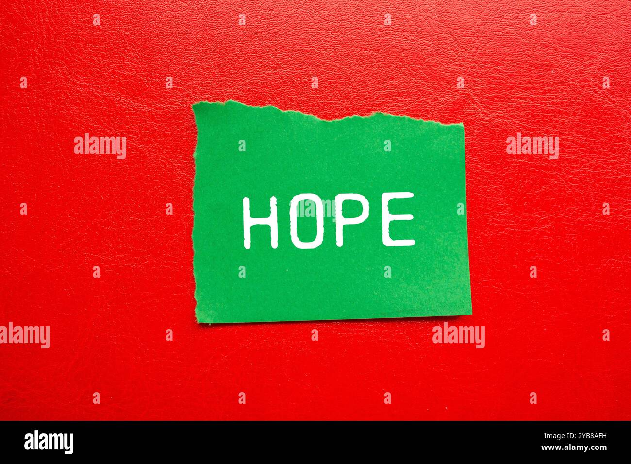 Hope message written on ripped torn green paper piece with red background. Conceptual hope ...