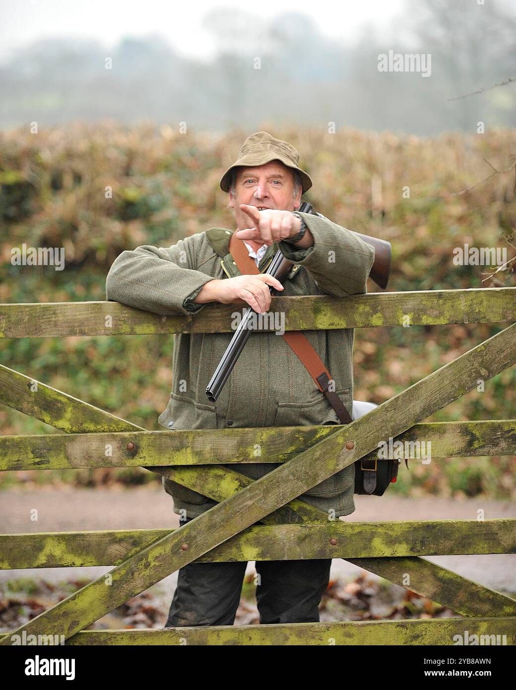 farmer with gun leaning on a gate and pointing at camera Stock Photo ...
