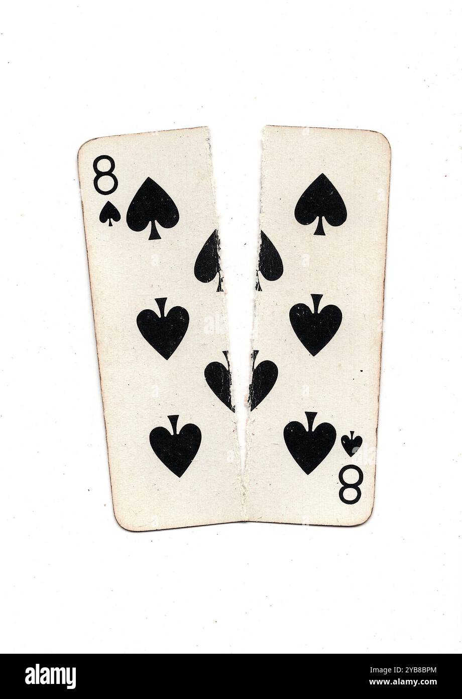 A vintage playing card torn in half from top to bottom on a white ...