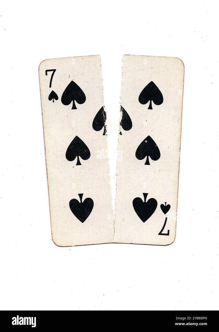 A vintage playing card torn in half from top to bottom on a white ...