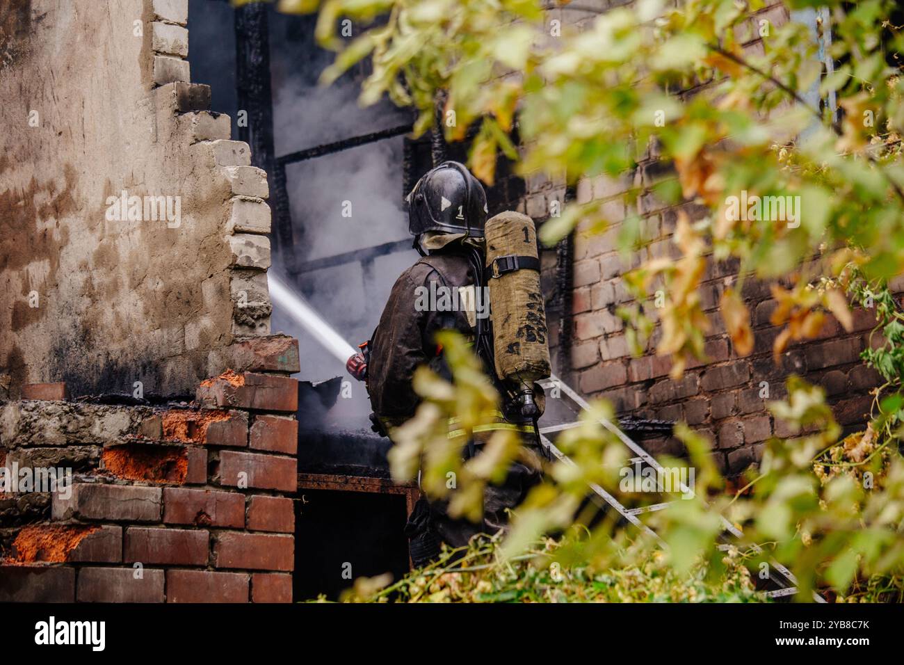 Firefighter extinguish fire in house using spraying hose Stock Photo ...