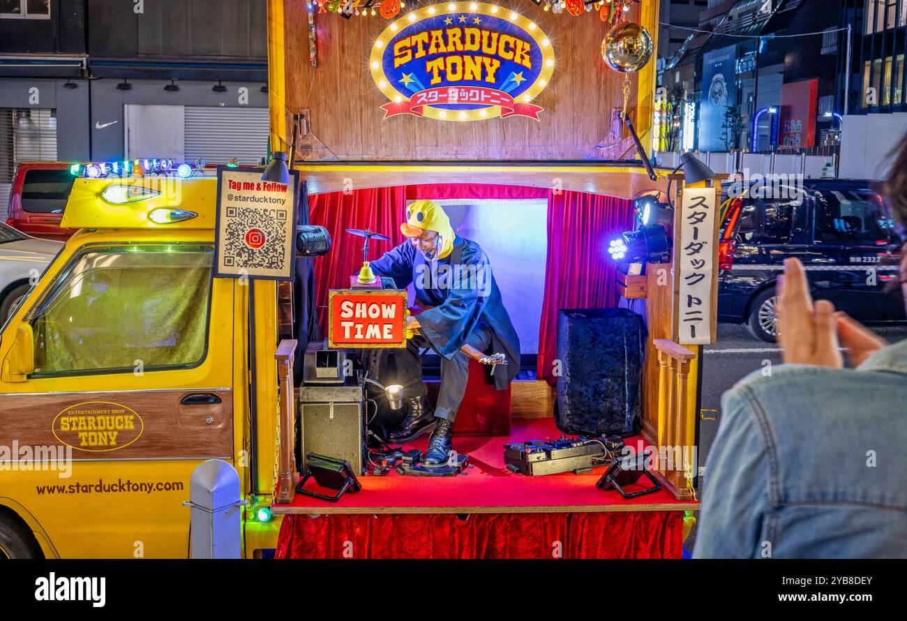 Busker performing from mini stage in back of small van outside Shinjuku ...