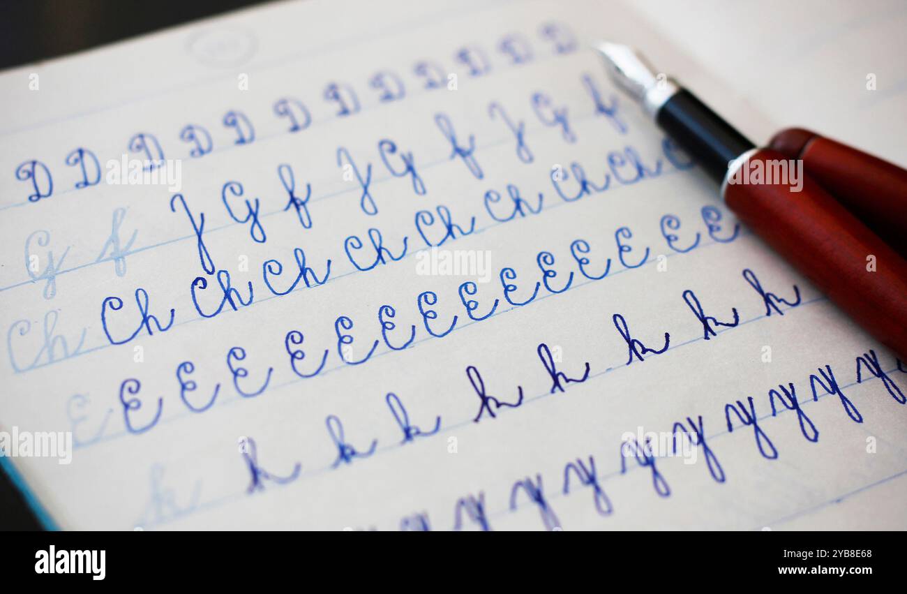Close-up of uppercase and lowercase letters written by a child in cursive with a fountain pen ...