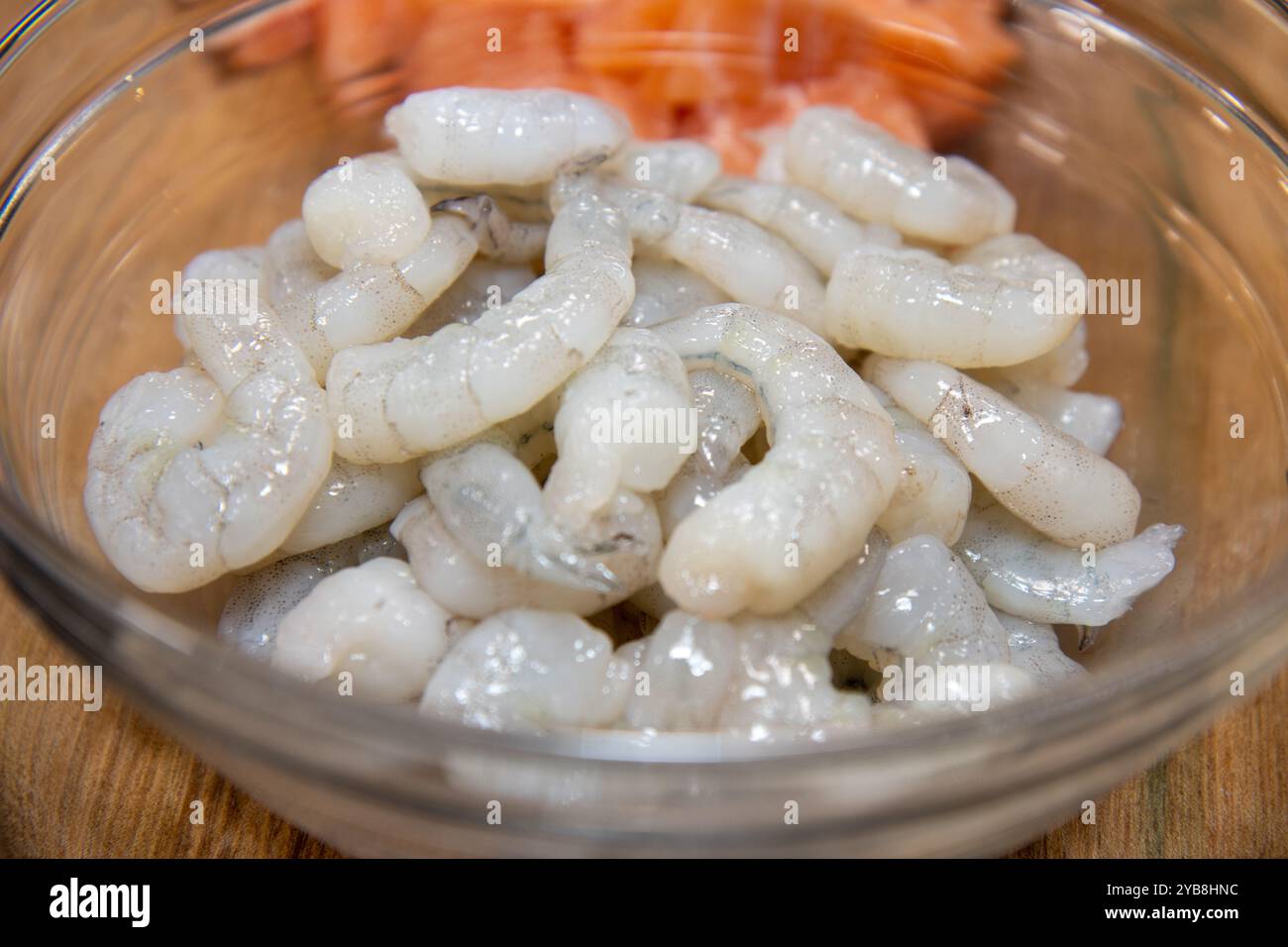 A glass bowl of fresh cut and peeled prawns ready to be placed in a ...