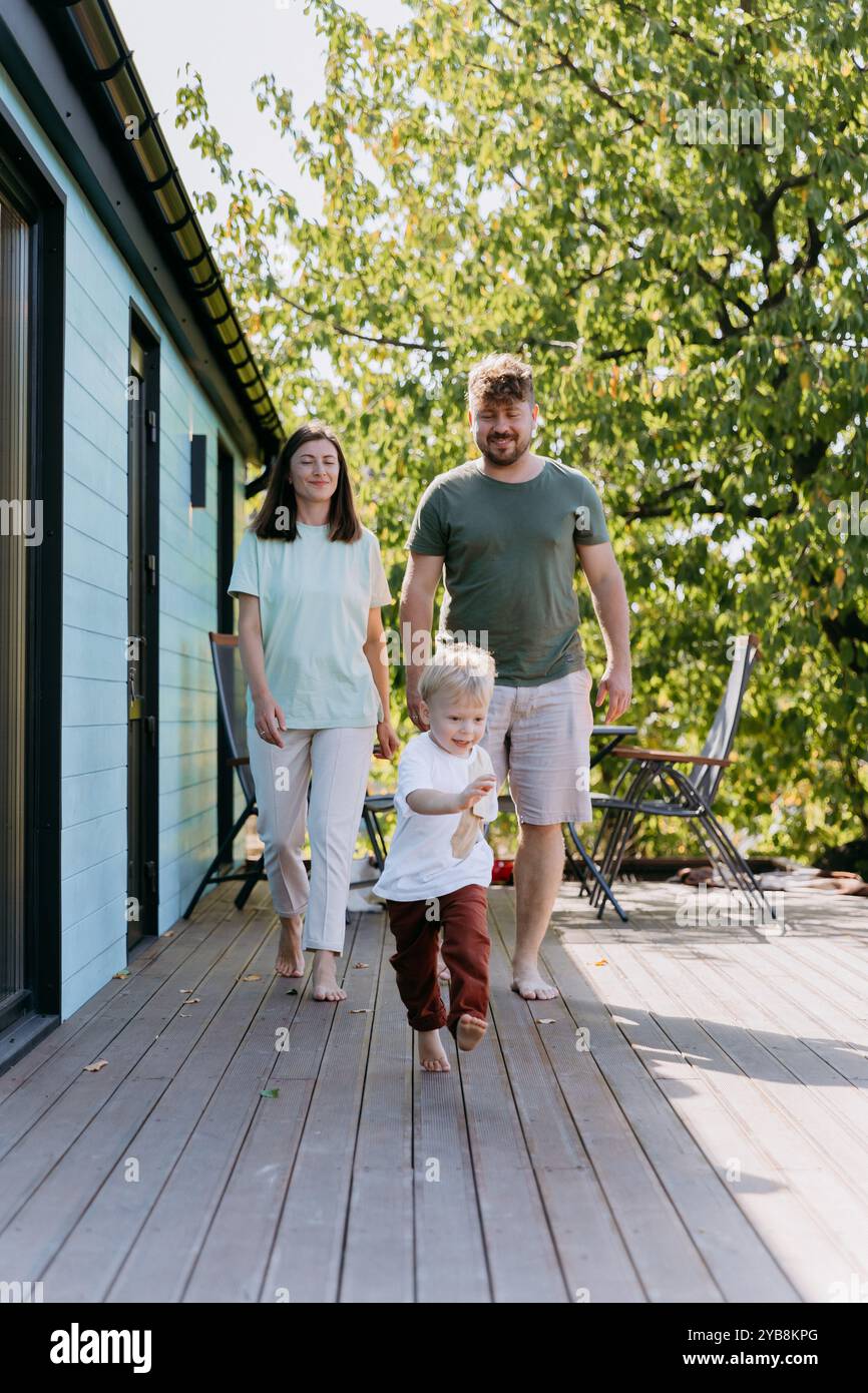 A joyful family walking together on a sunny day, with their child ...