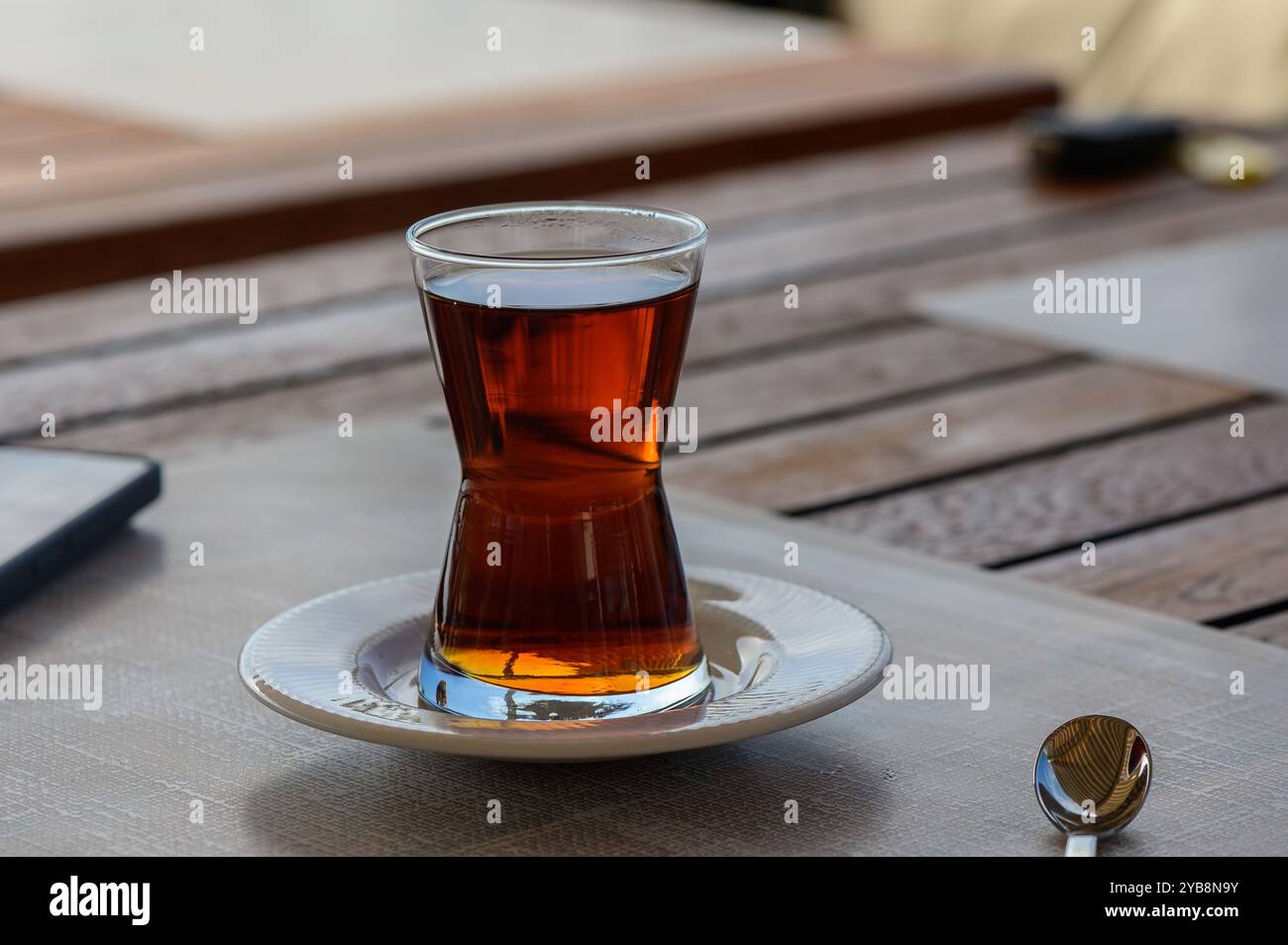 The sunlight gently illuminates a glass of herbal tea placed on a ...