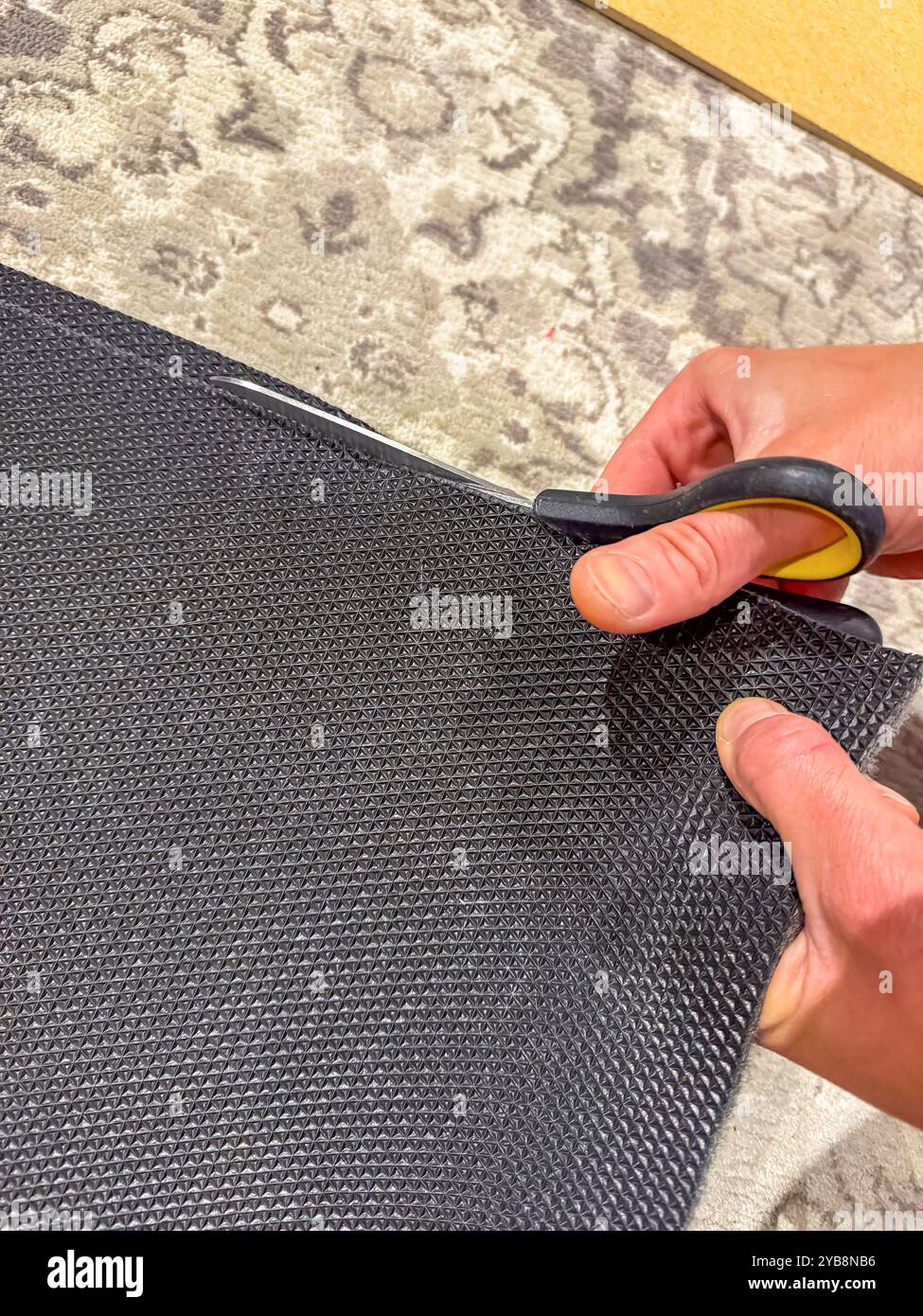 Closeup of hands holding scissors and cutting black rubber fabric ...
