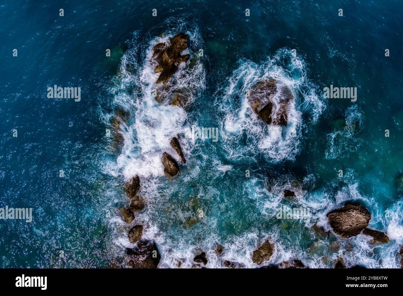Aerial view of powerful ocean waves crashing against jagged rocks in ...