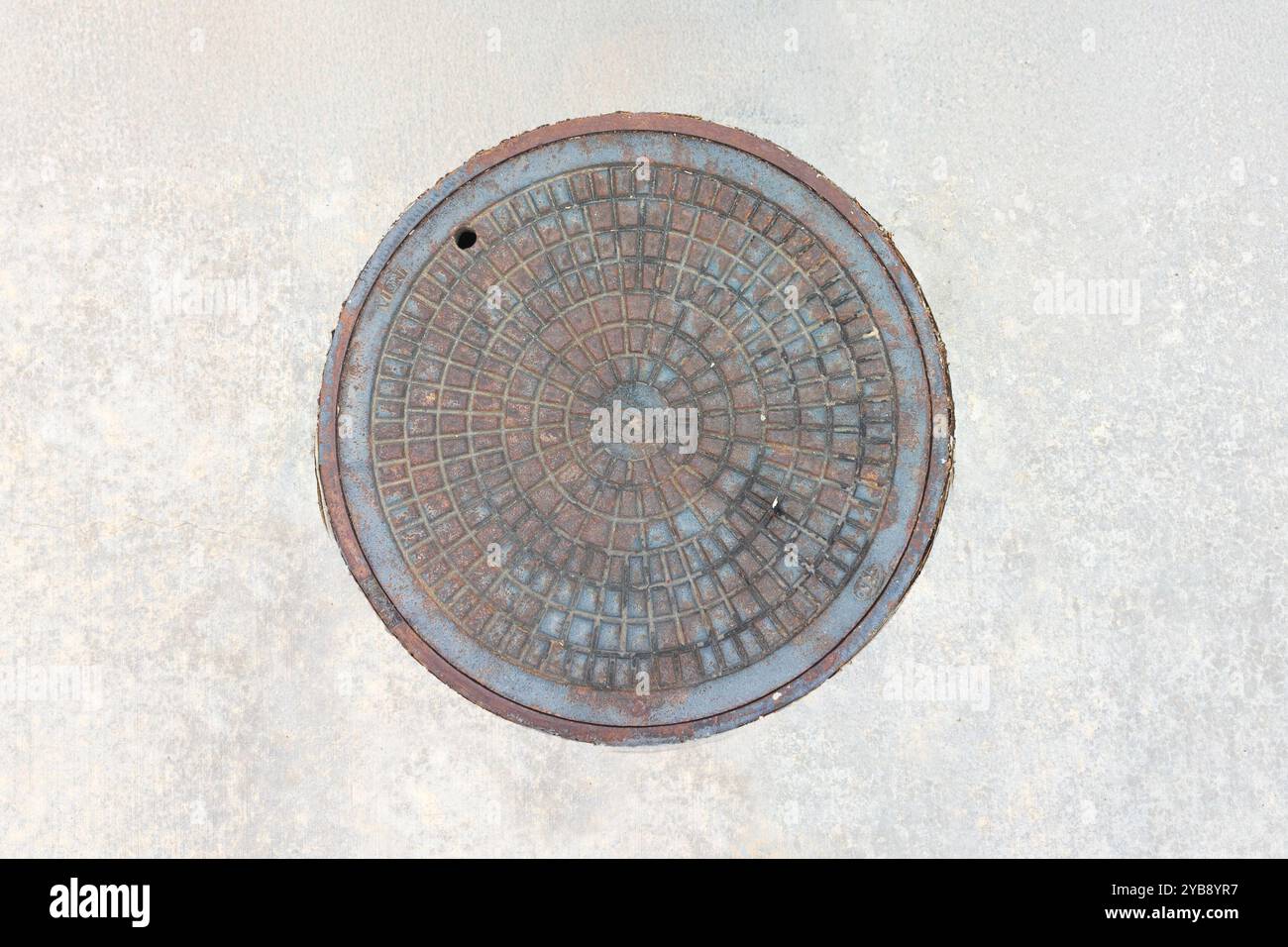 Overhead view of metal manhole cover set in concrete Stock Photo - Alamy