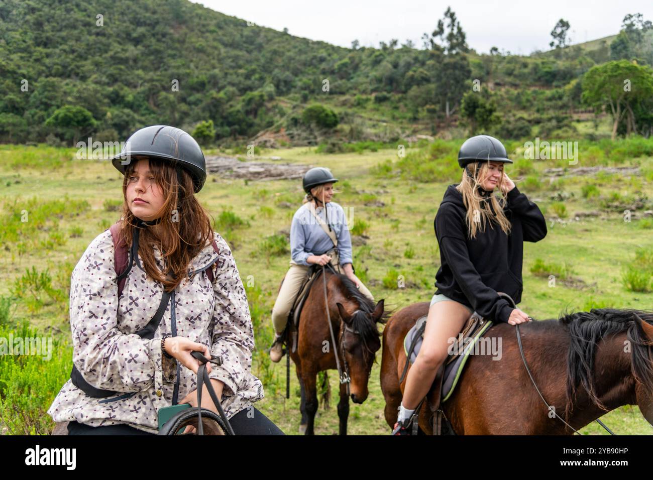 Three female horse riders riding a horse on a safari at Botlierskop ...