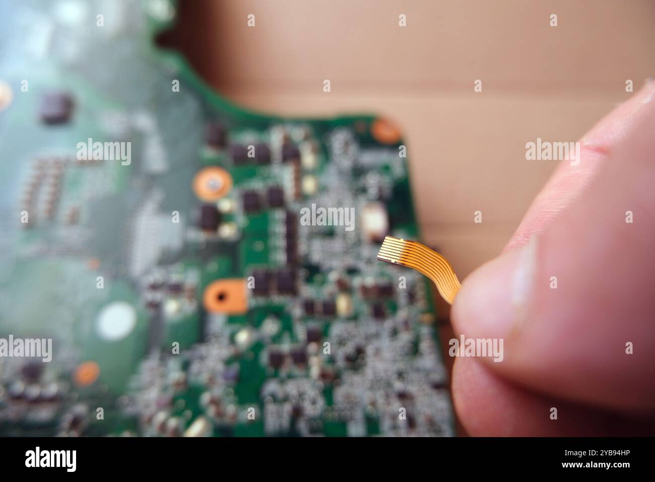 Technician holding 8-pin flexible flat ribbon cable on a high ...