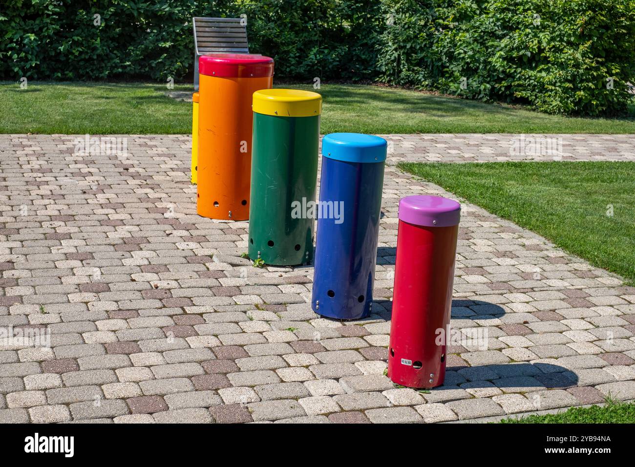 Vibrant cylindrical structures stand on a paved area in a park ...
