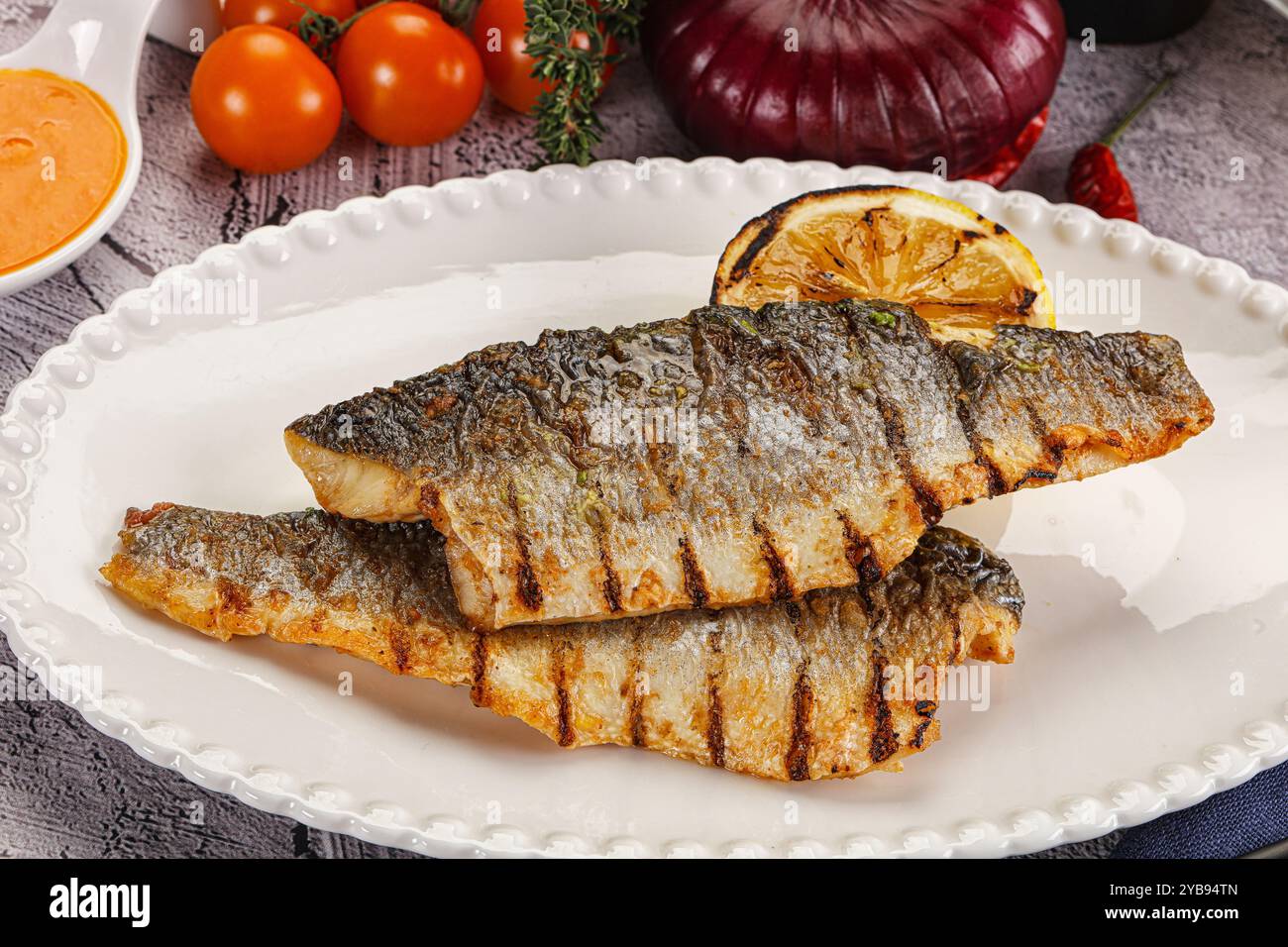 Grilled seabass fillet with lemon and sauce Stock Photo - Alamy