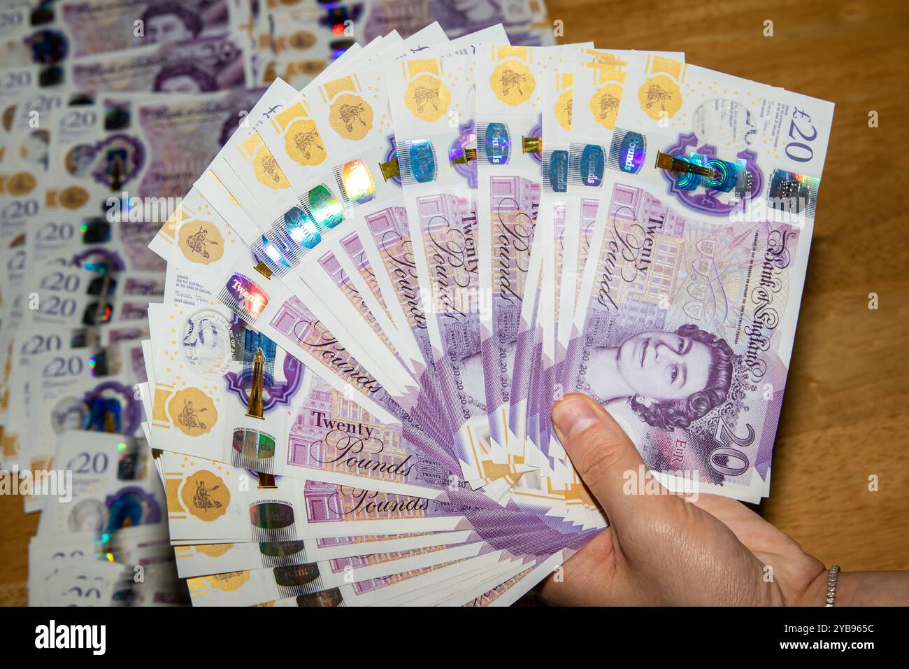 A hand holding a fan of twenty-pound banknotes, showcasing the vibrant ...