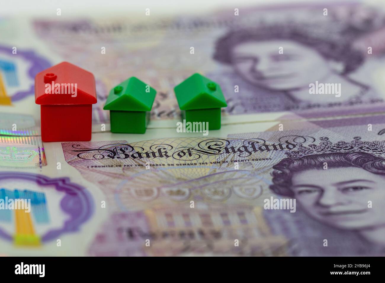Three toy houses, one red and two green, sit on a twenty pound note ...