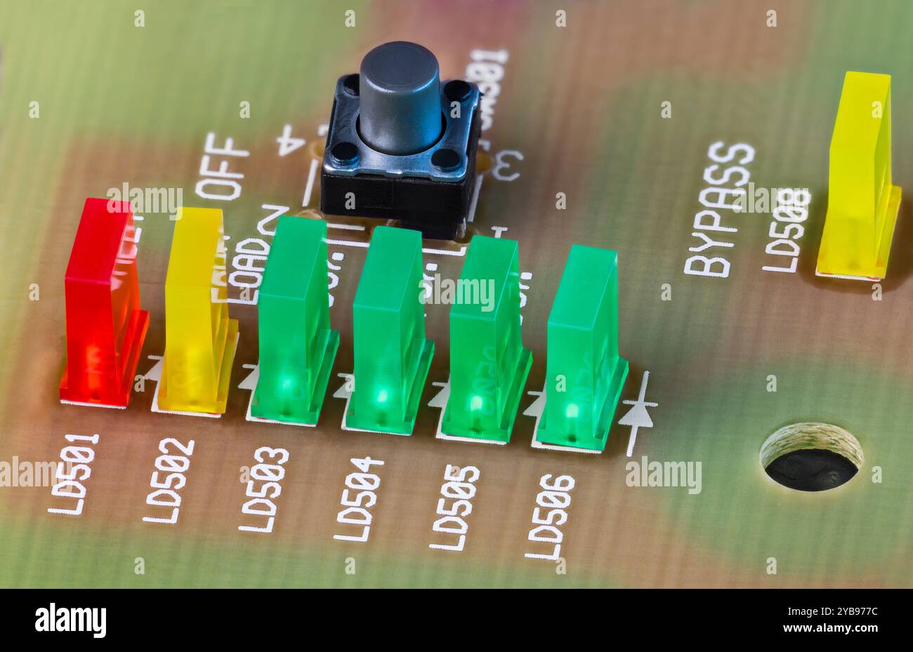 Closeup of colored LED lights and black button on printed circuit board ...