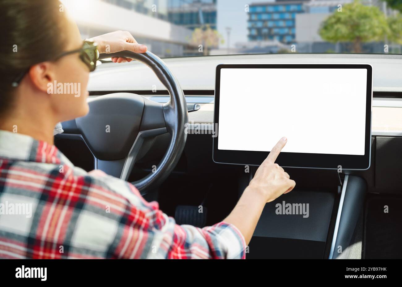 Woman engaging with infotainment system in electric car interior ...