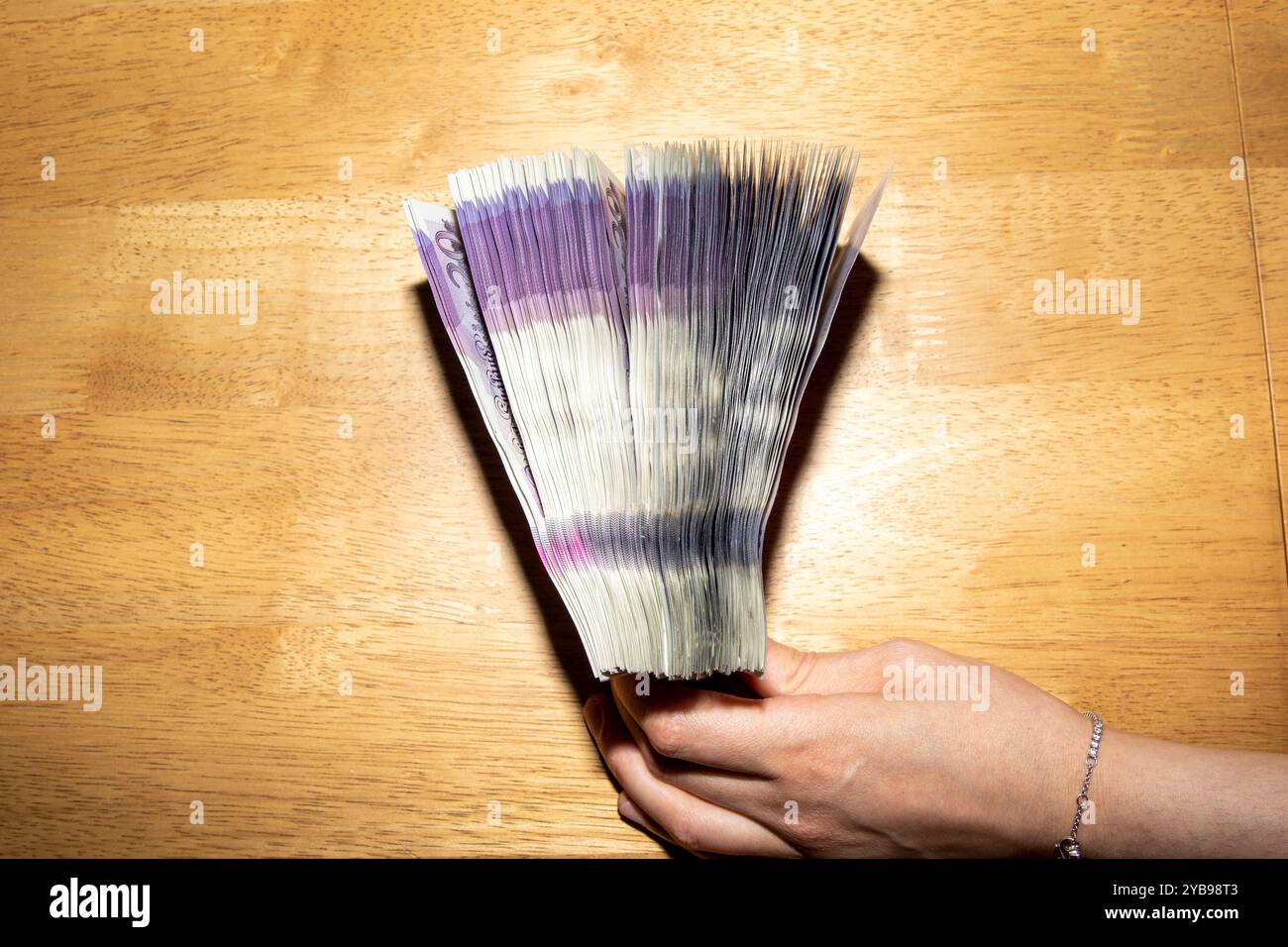 A hand holding a large stack of banknotes, showcasing various ...