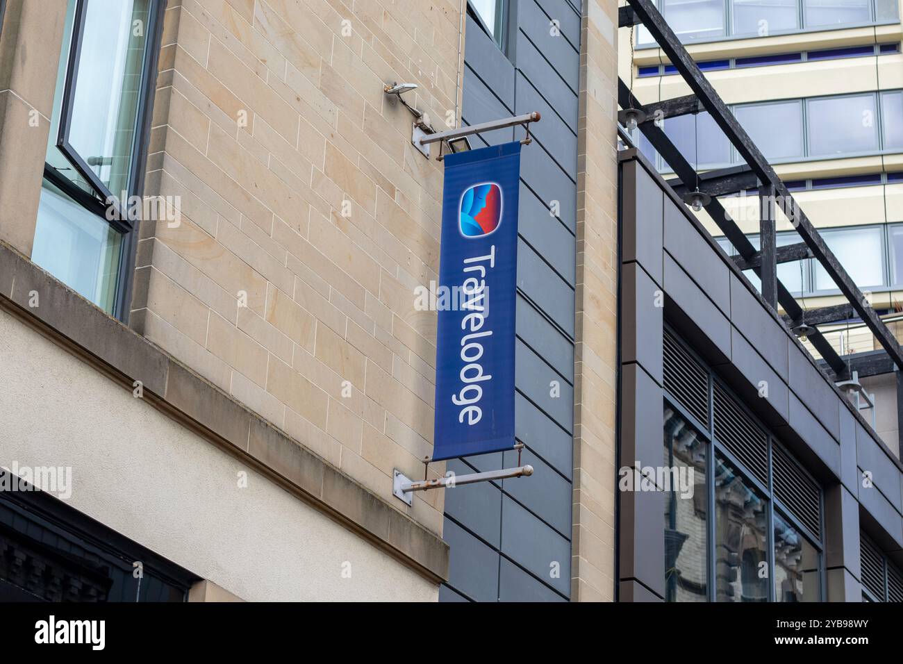 A blue and red sign hanging from a building, displaying the Travelodge ...