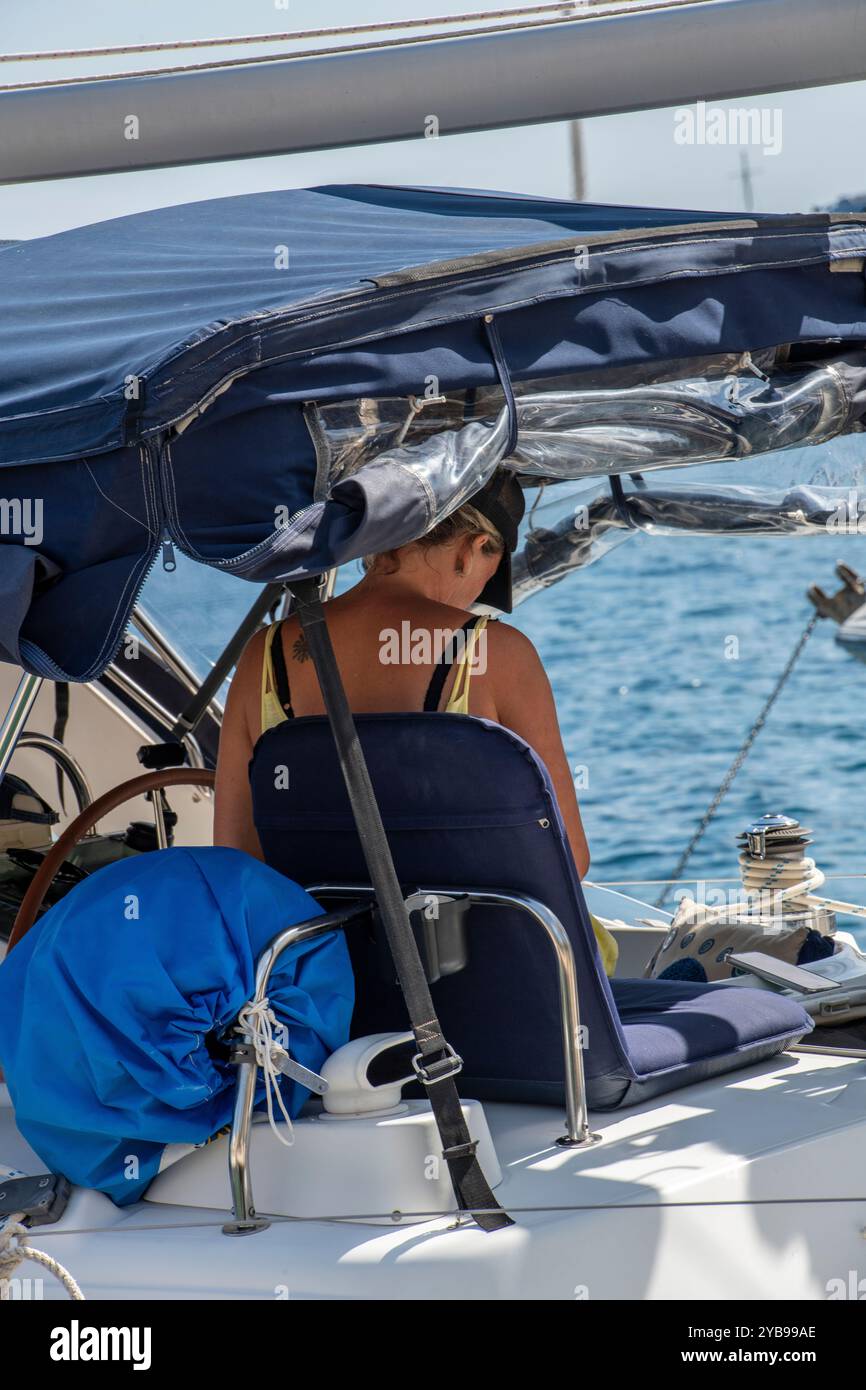female sitting in the cockpit of a large cruising yacht in a ...