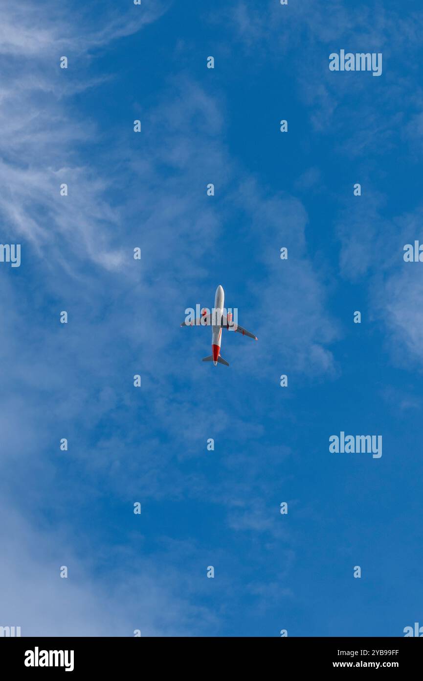 underside of jet airliner aircraft flying against a clear blue sky with ...