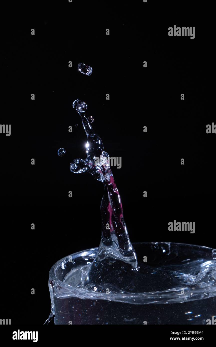 A series of water droplets are captured mid-flight as they splash ...