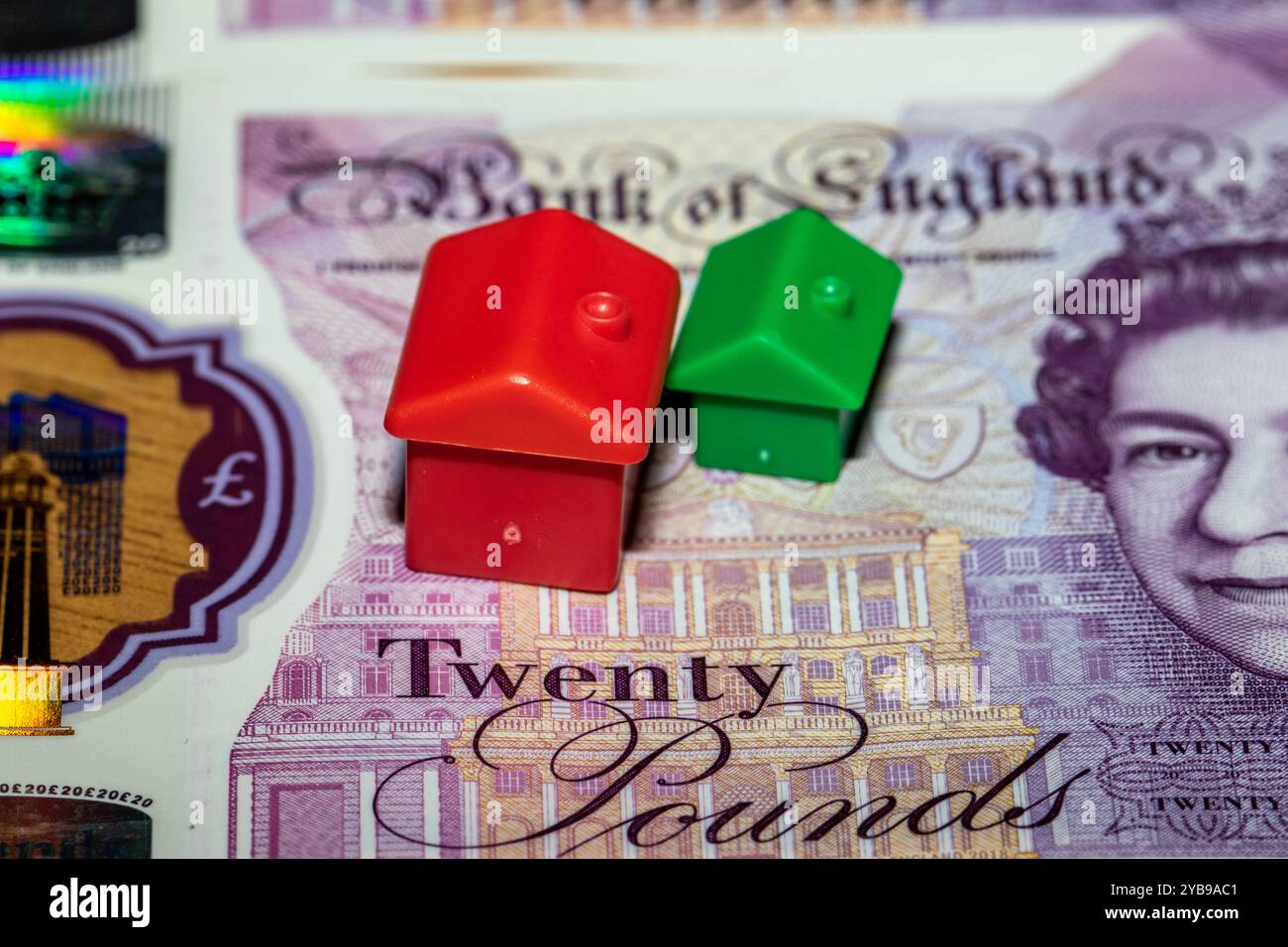 Two toy houses, one red and one green, sit atop a British twentypound ...