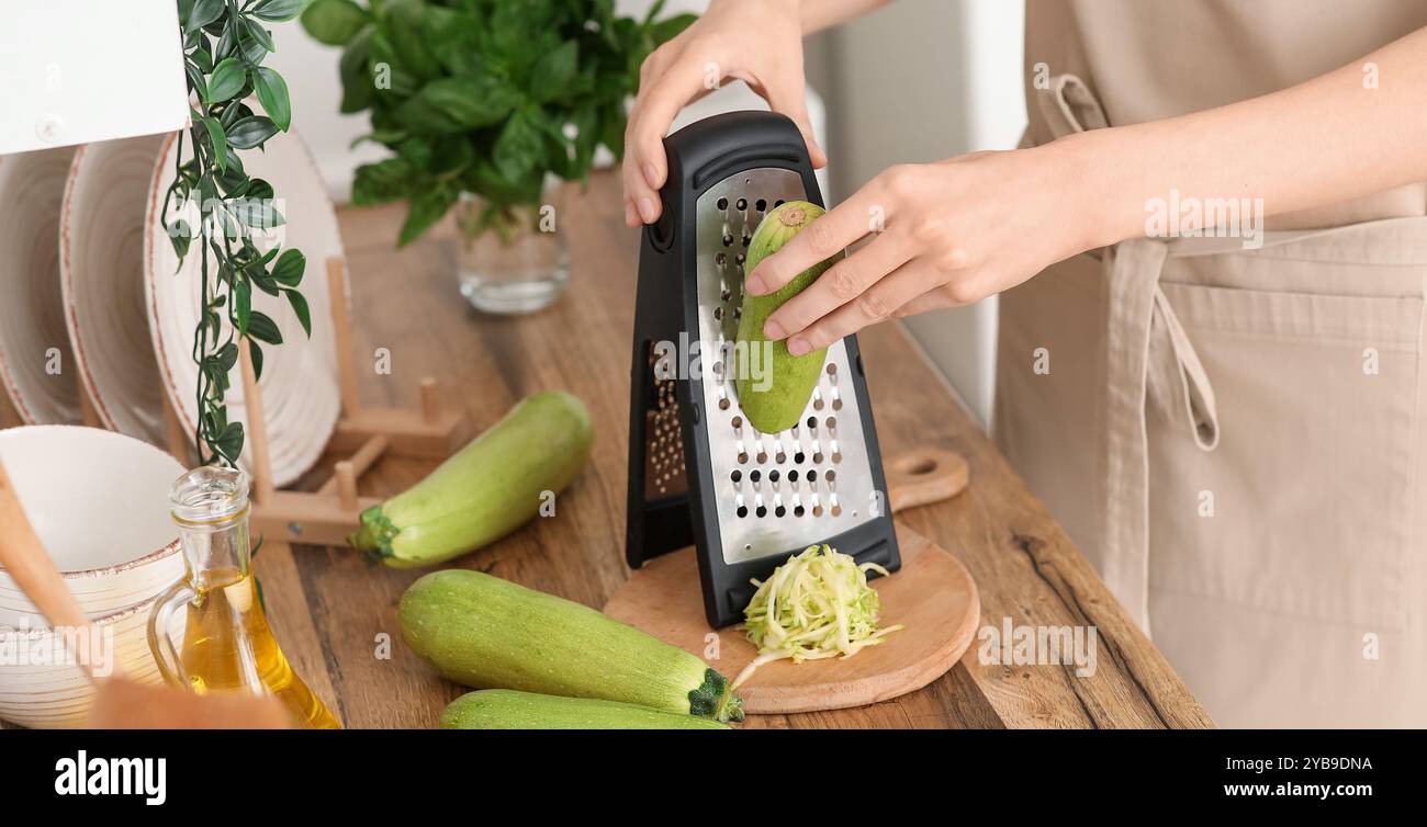 Young woman grating fresh zucchini in kitchen Stock Photo - Alamy